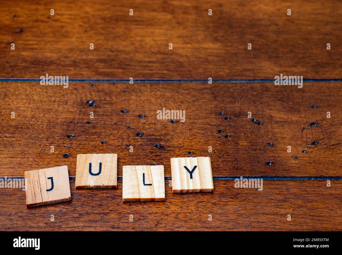 July word on letter tiles on wooden background with copy space Stock ...