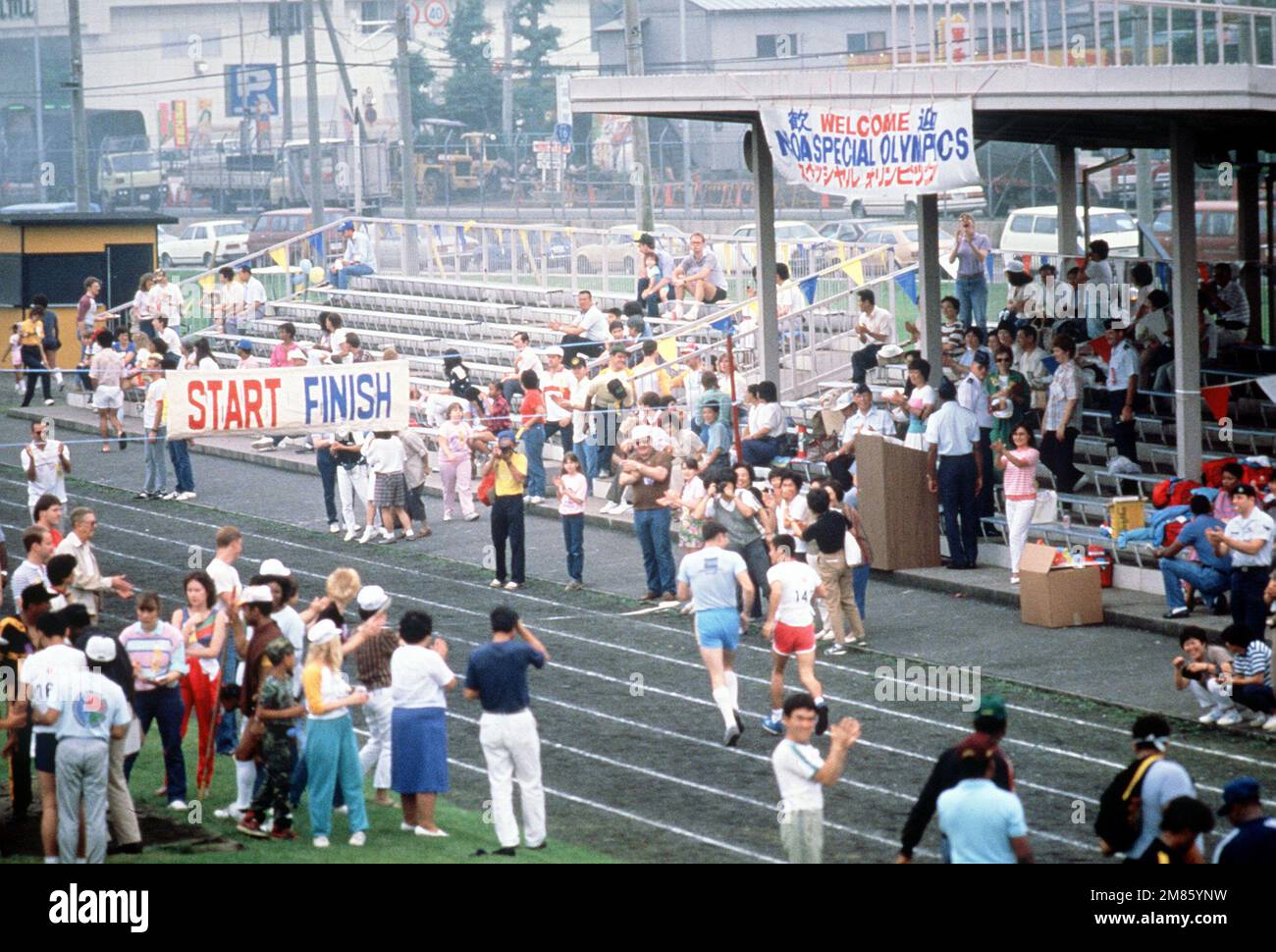 Family, friends and helpers gather around the finish line as a ...