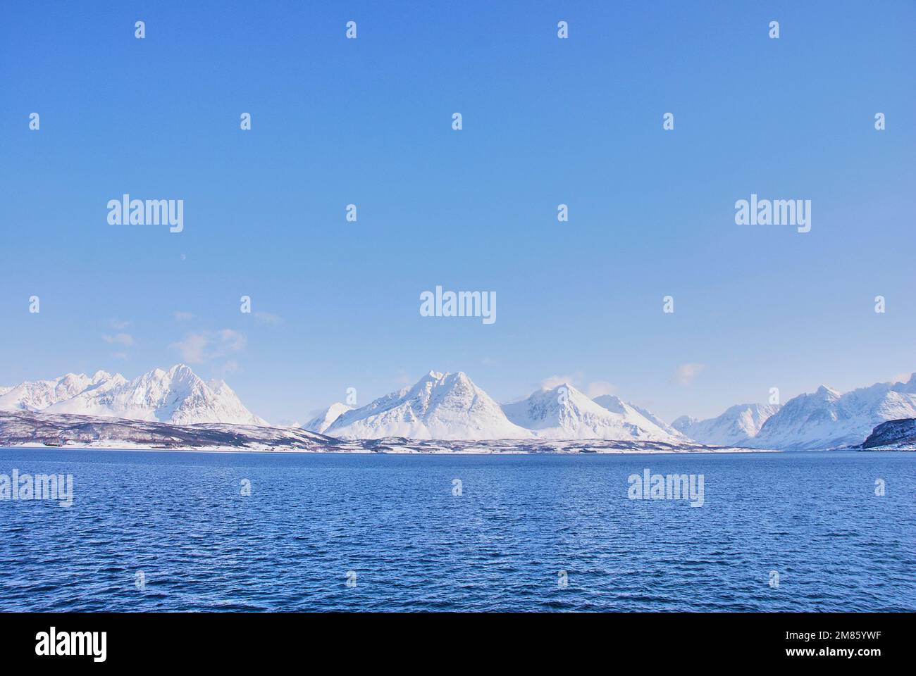 winter landscape with snow covered mountains on a fjord in the artic ...