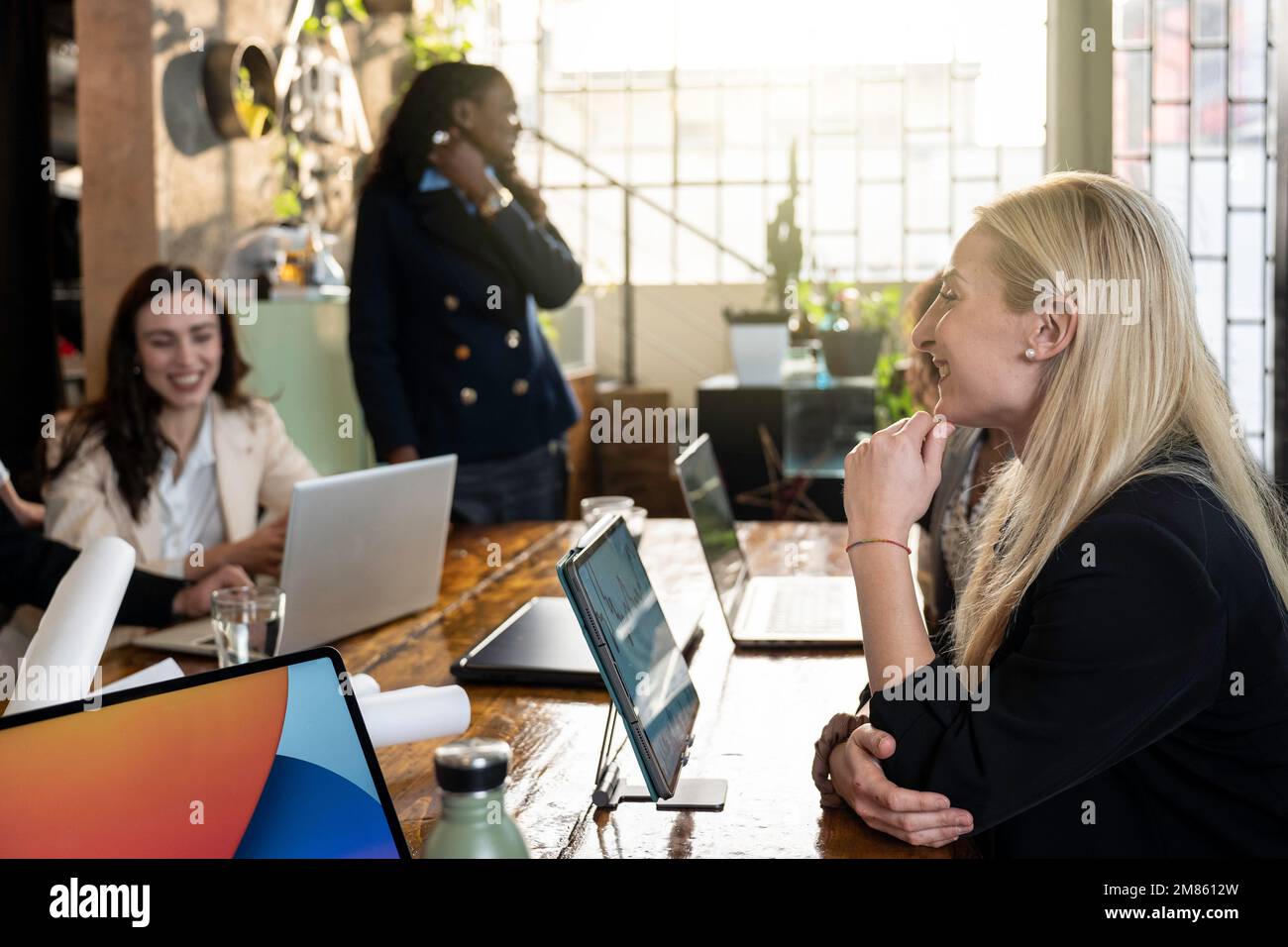 Businesswomen laugh together in modern coworking office during break ...