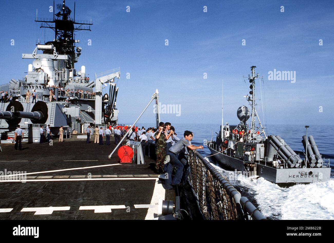 Crew members aboard the battleship USS IOWA (BB-61) watch from the rail ...