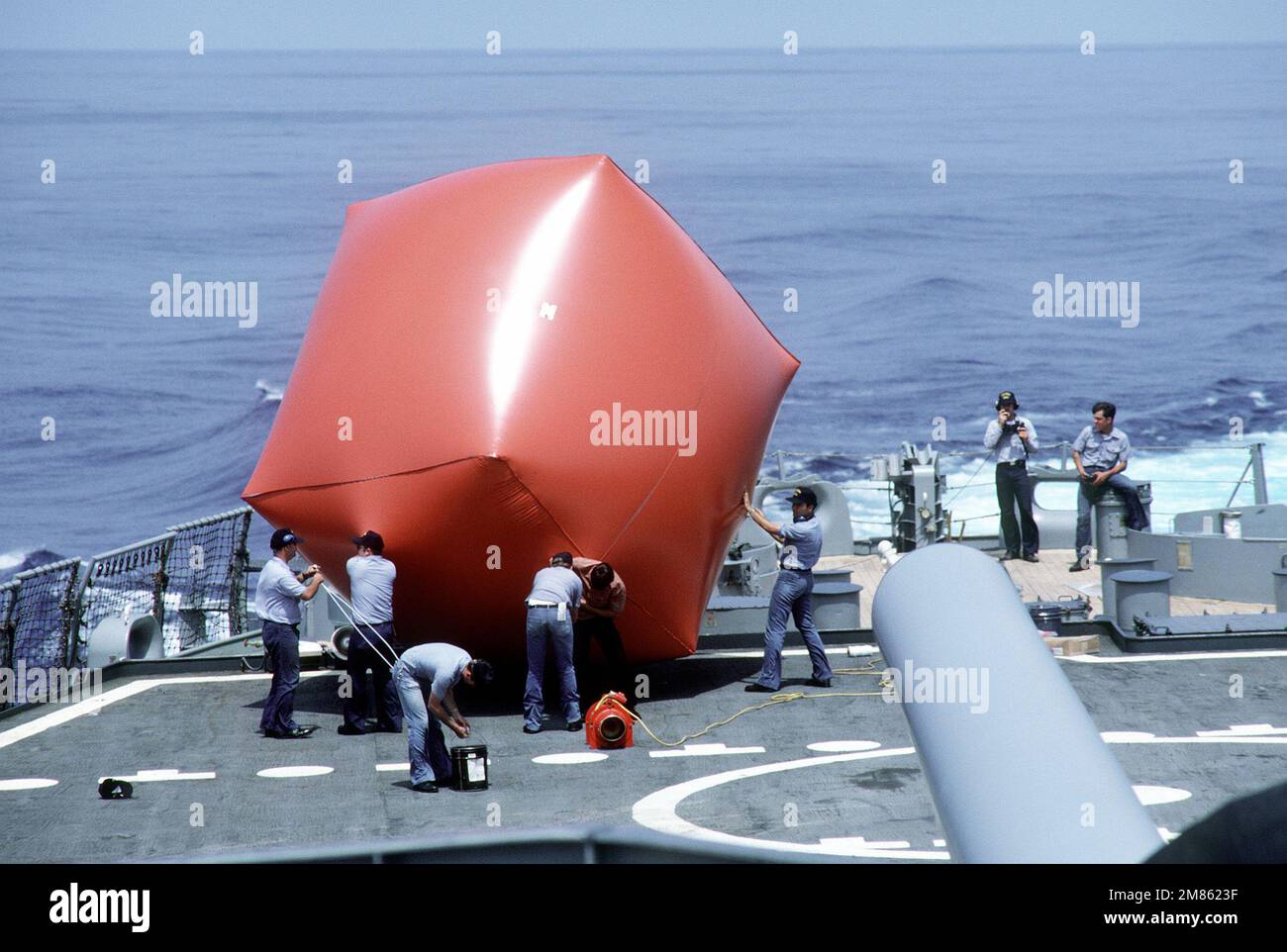 Crew members inflate a large target float on the stern in preparation ...
