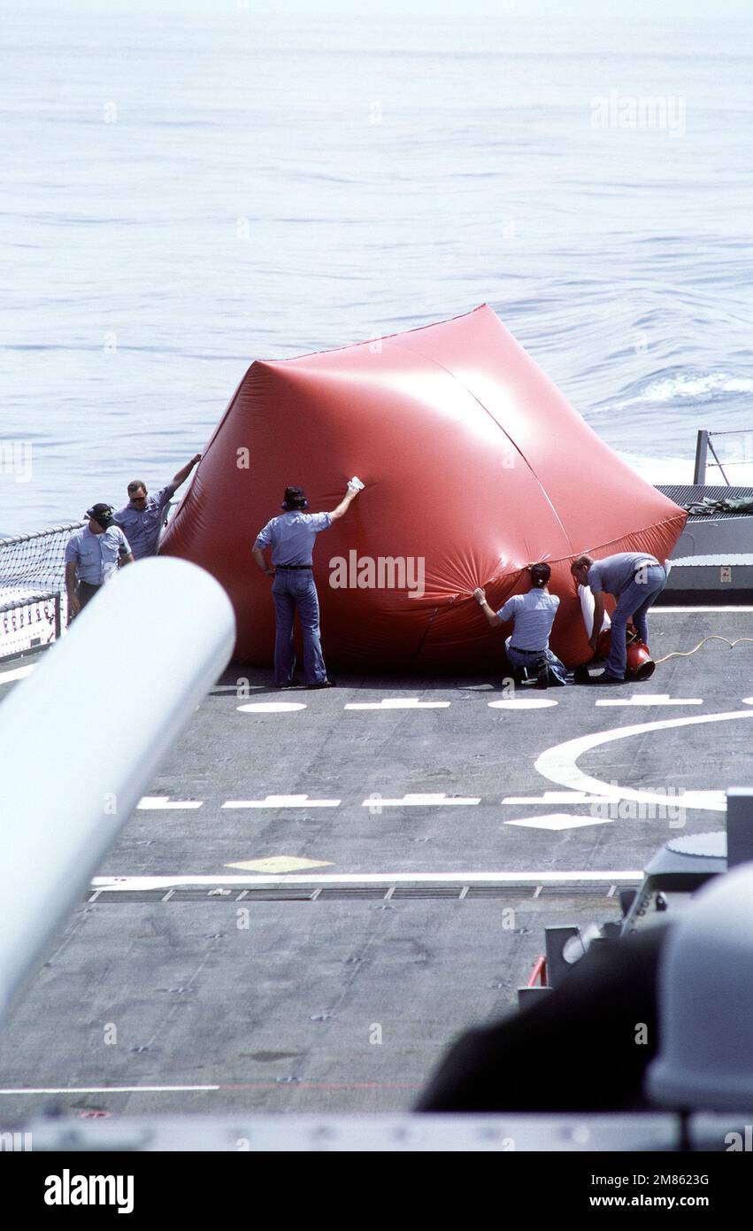 Crew members inflate a large target float on the stern in preparation ...