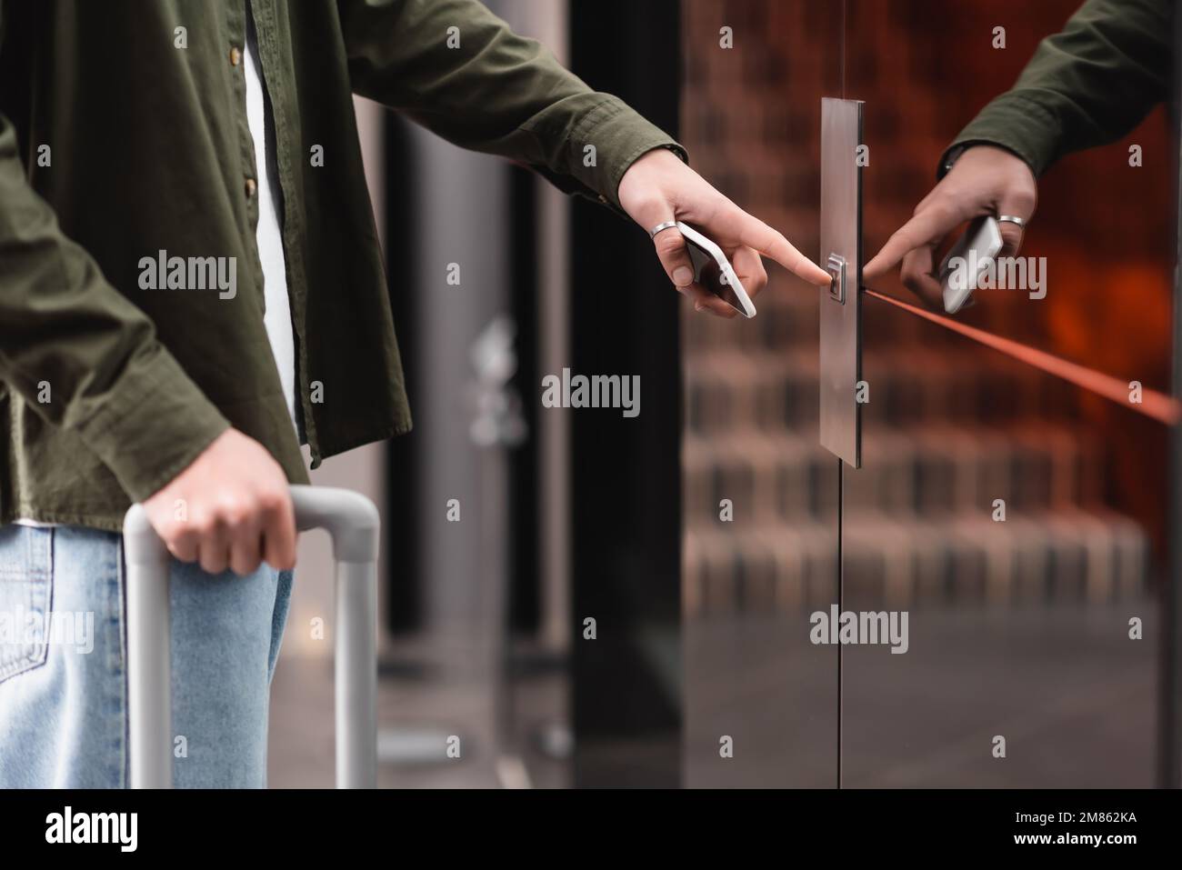 cropped view of man with mobile phone pressing elevator call button in ...