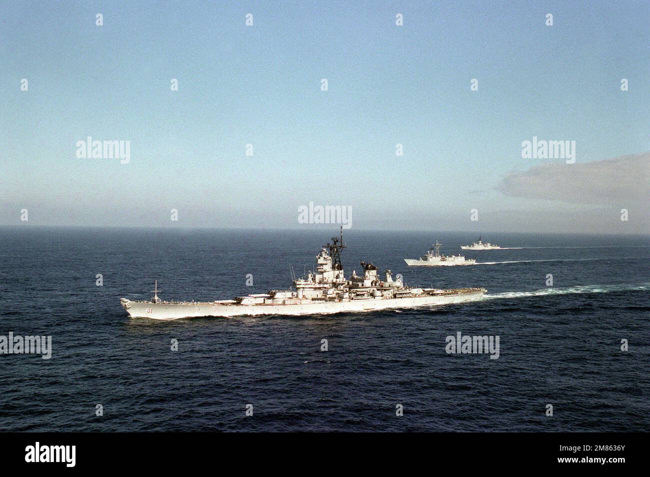 An aerial port bow view of the battleship USS IOWA (BB-61), foreground, the guided missile ...