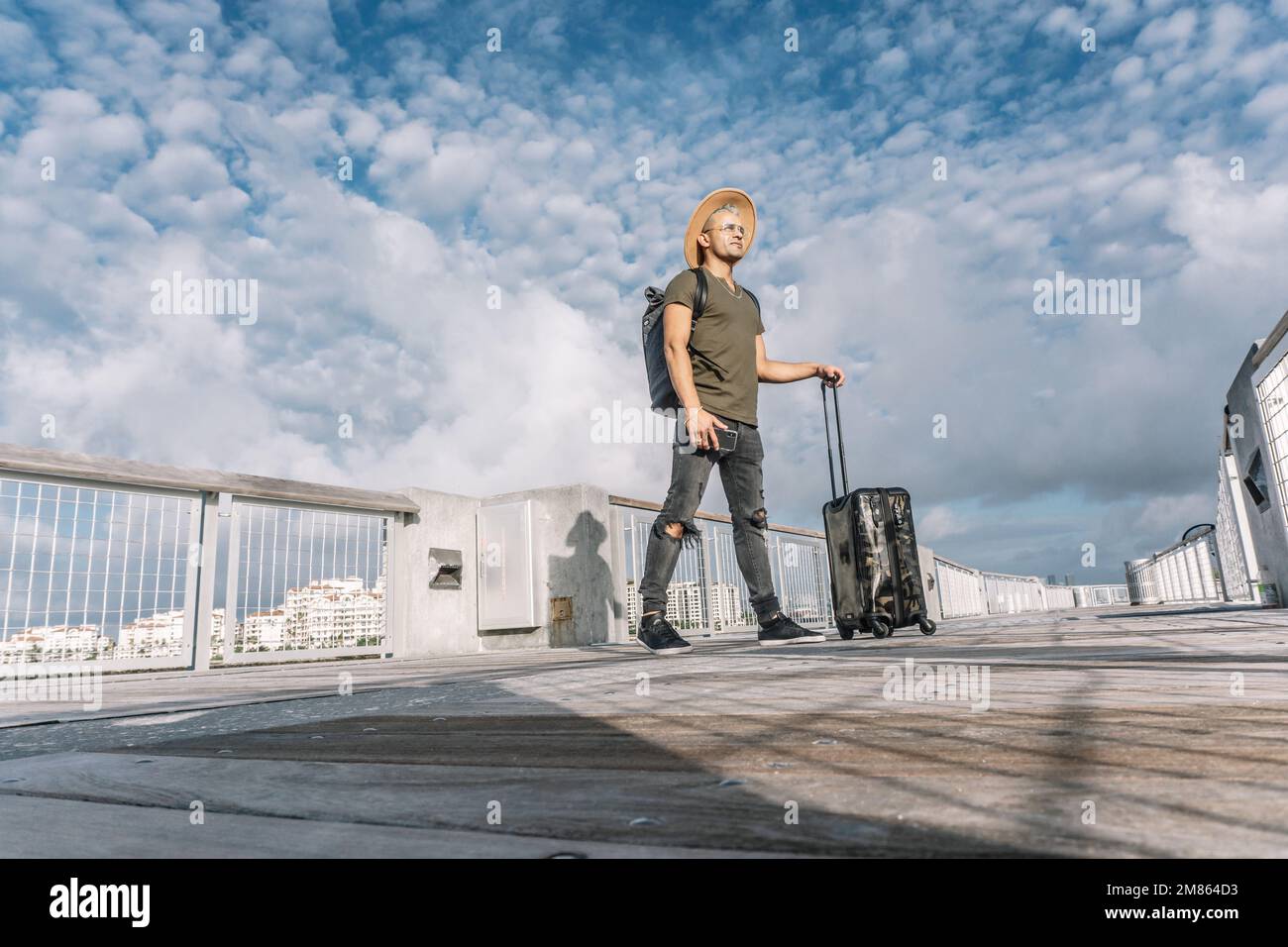 Full length side view serene tourist holding luggage while stands in a ...