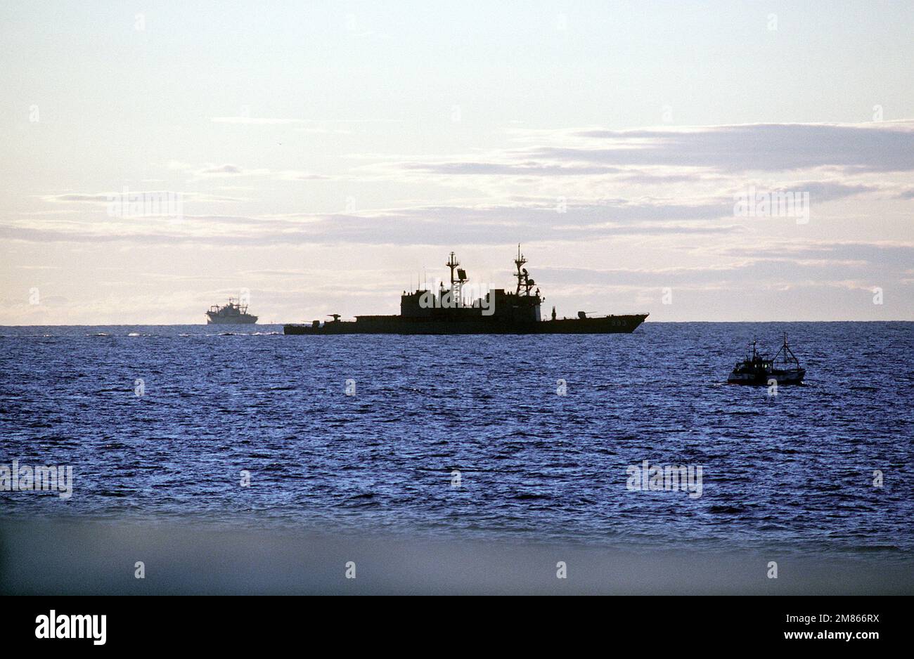 A silhouetted starboard beam view of the guided missile destroyer USS ...
