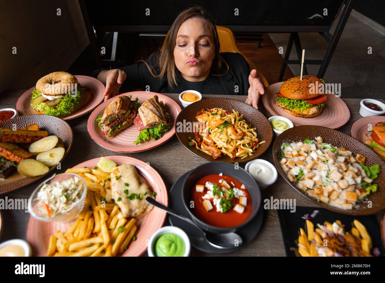 Hungry woman with pleasure smell flavor of delicious food in plates ...