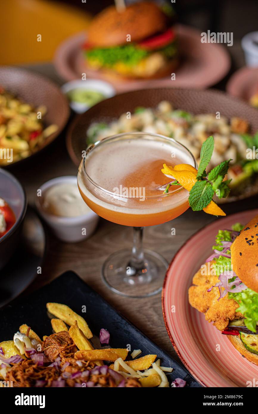 Glass of alcoholic cocktail with mint and orange decor on table full of ...