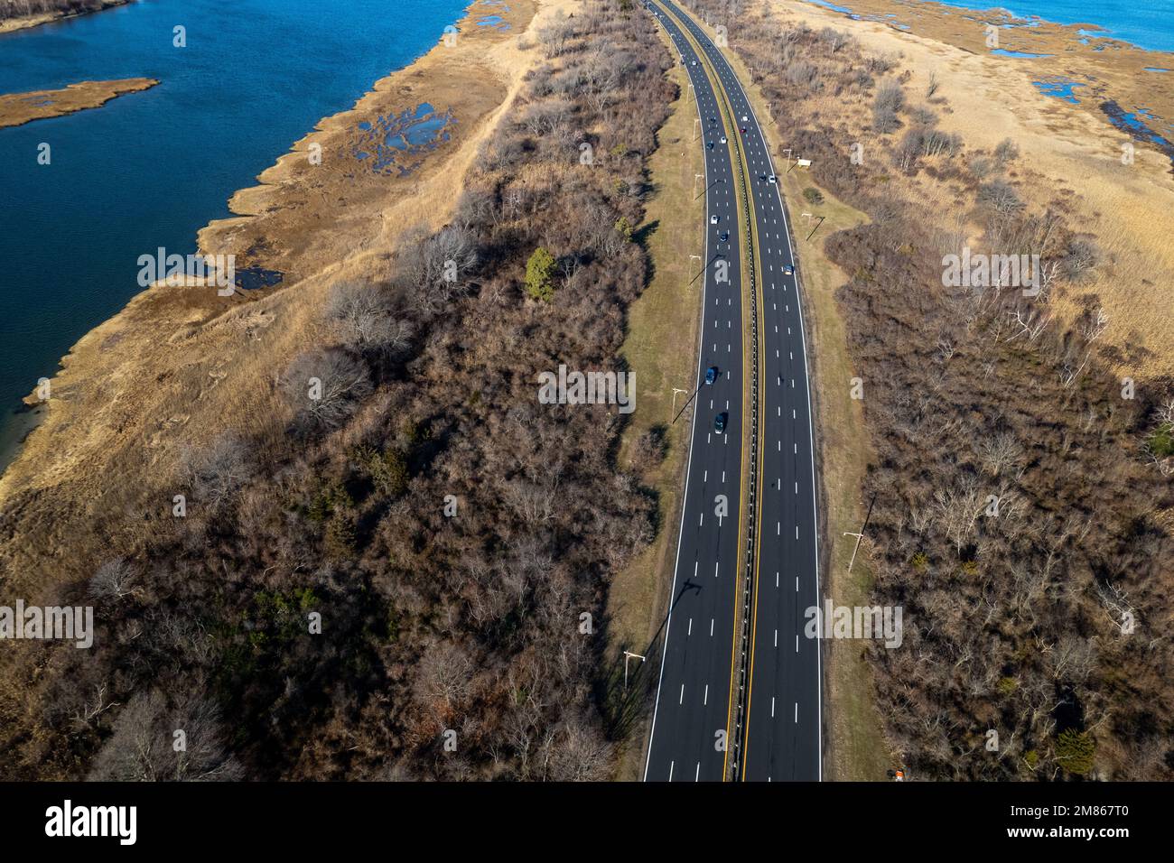 An aerial top view of cars on the highway running through a salt marsh ...