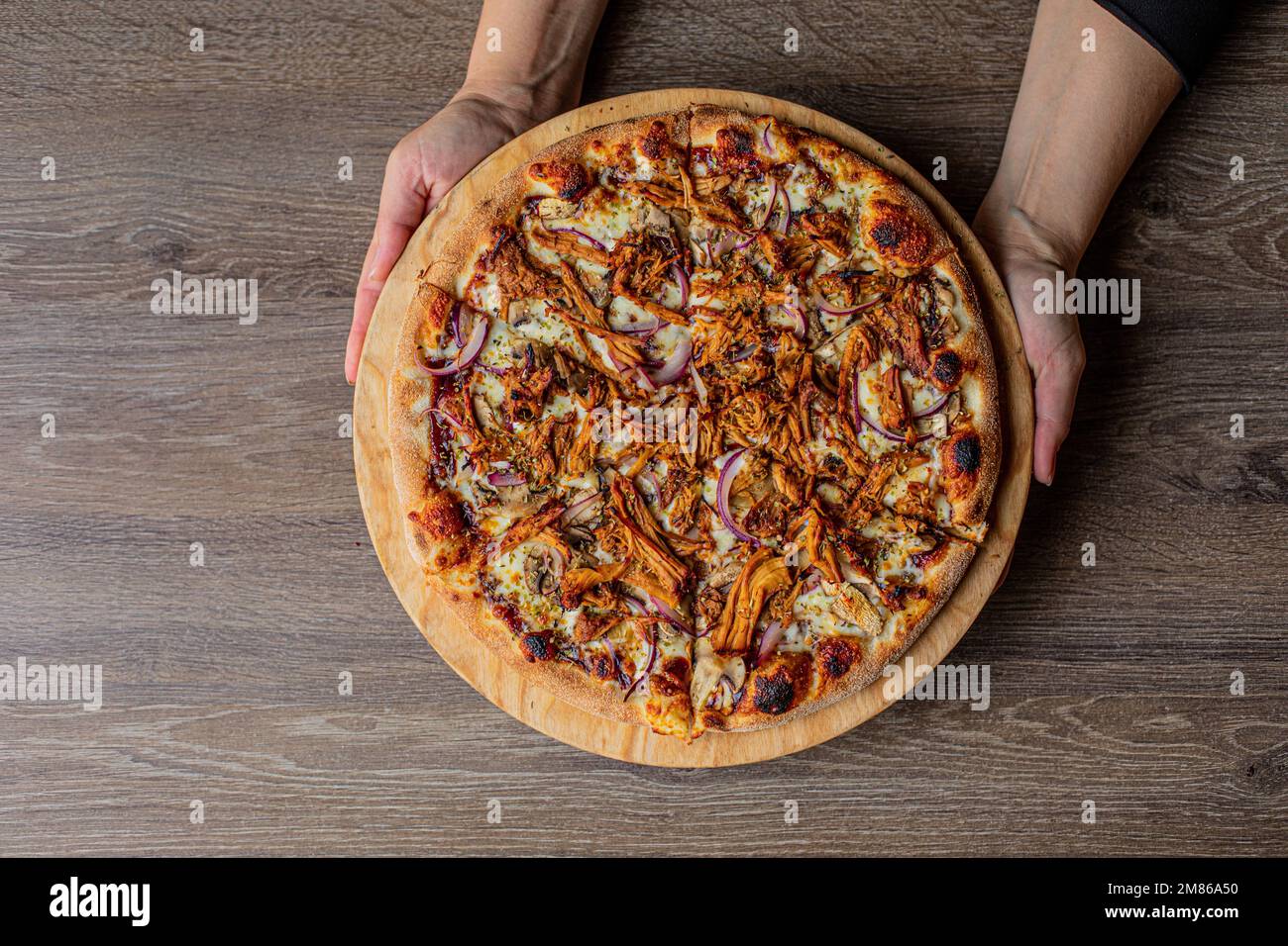 Hands of waiter hold wooden tray of fresh appetizing pizza isolated on ...
