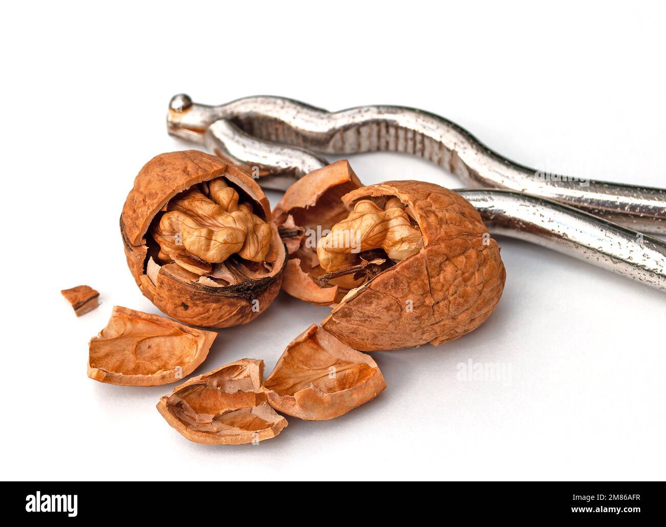 Walnuts and nutcracker against white background Stock Photo - Alamy