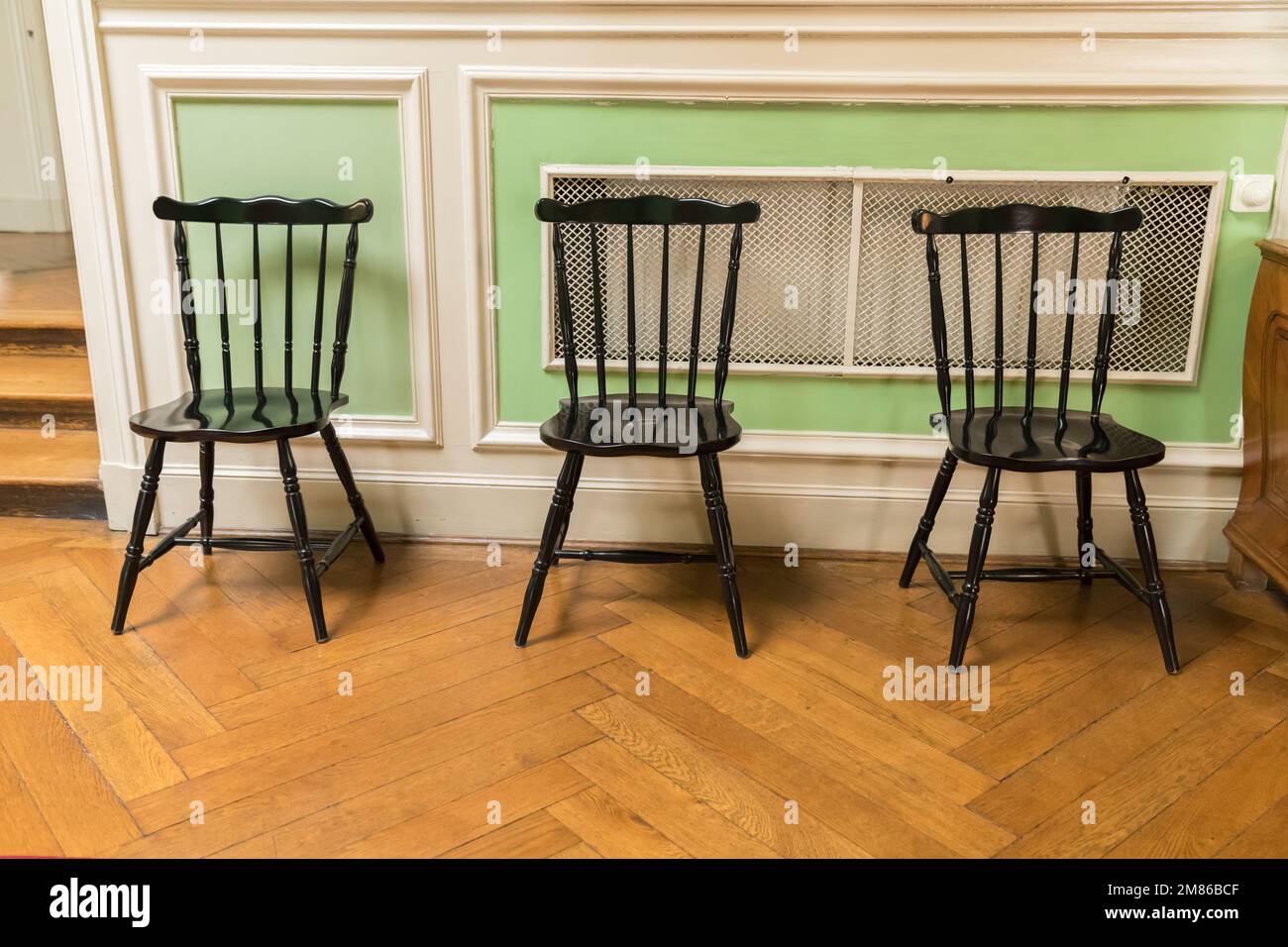 Three stylish wooden chairs lined up against the wall Stock Photo - Alamy