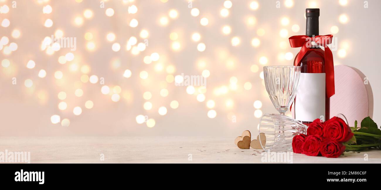 Bottle of wine, red rose flowers and glasses on light background with ...