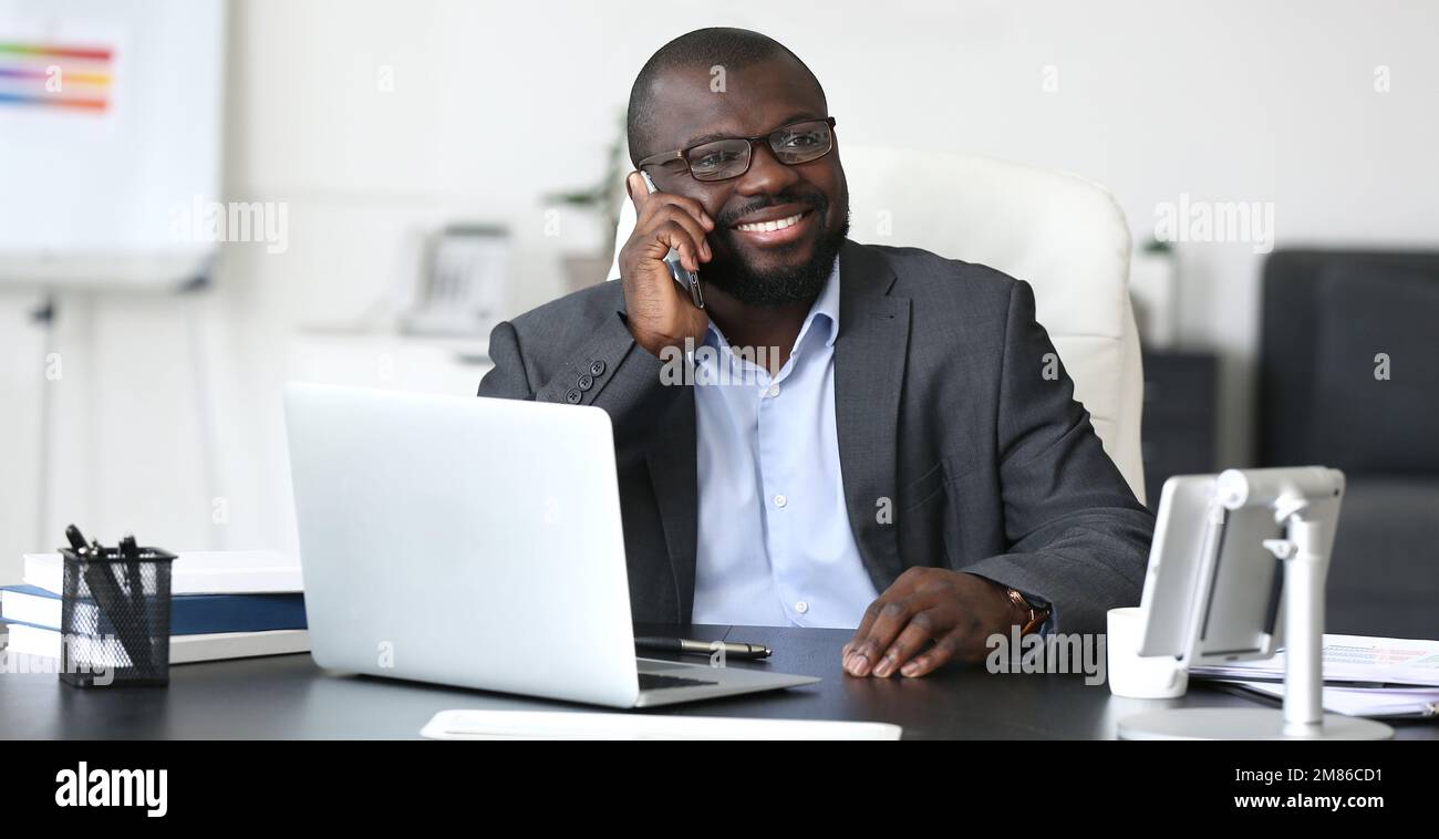 Handsome African-American businessman talking by phone while working in ...