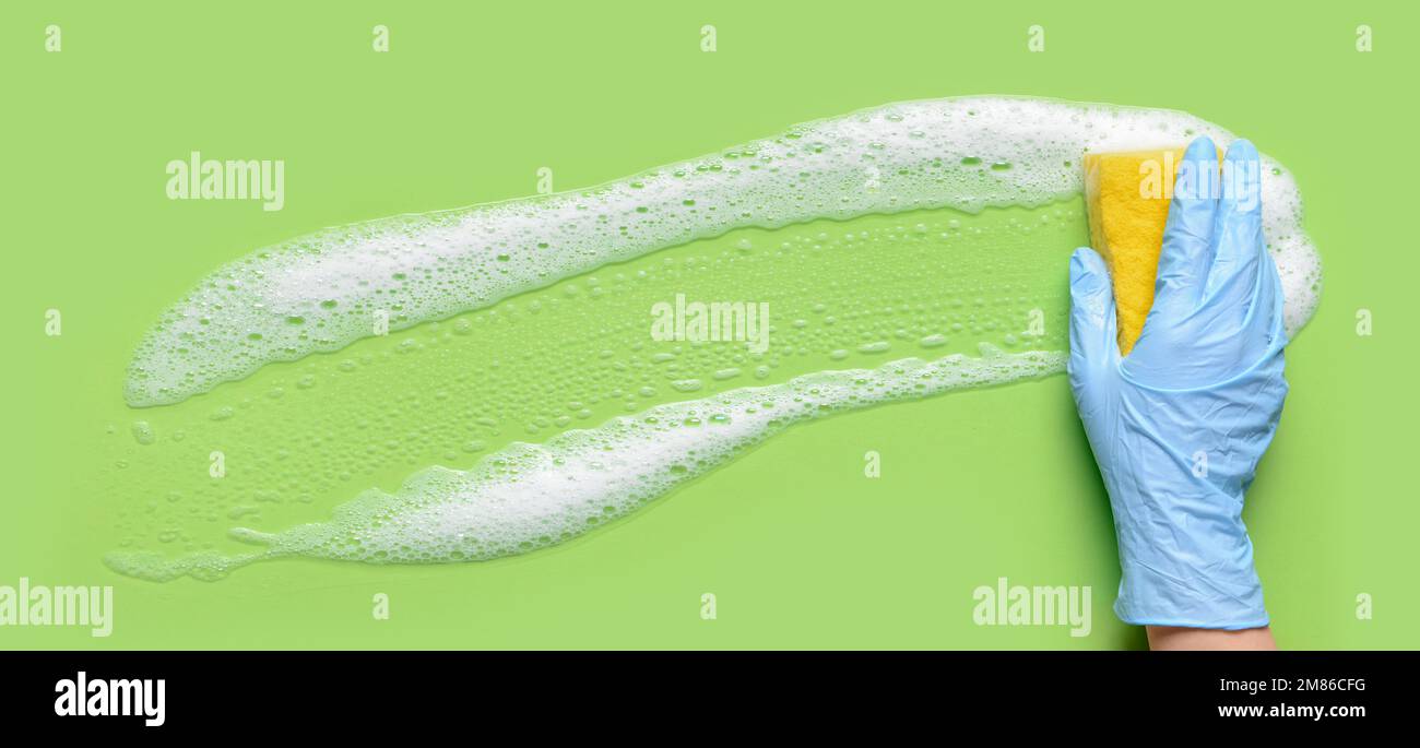 Hand with sponge cleaning green surface Stock Photo - Alamy