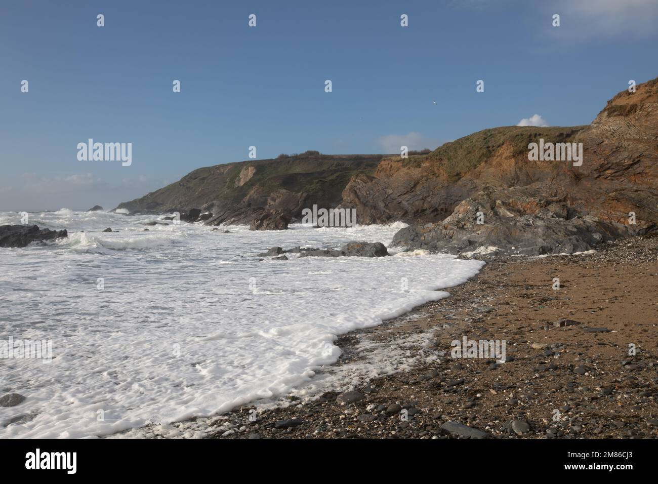 Seashore scene showing frothy white sea water rolling onto a Beach at ...