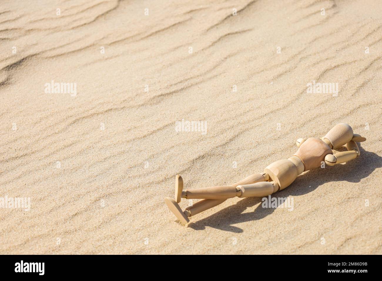 Wooden mannequin lying on sand Stock Photo - Alamy