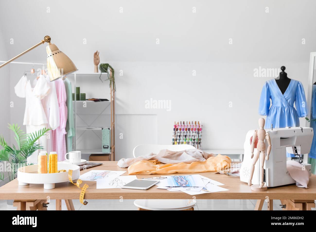 Interior of light atelier with tailor's workplace, clothes and ...