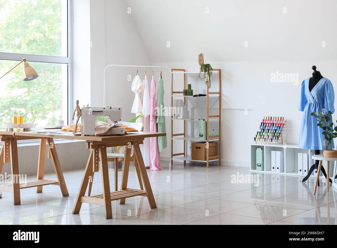 Interior of light atelier with tailor's workplace, clothes and ...