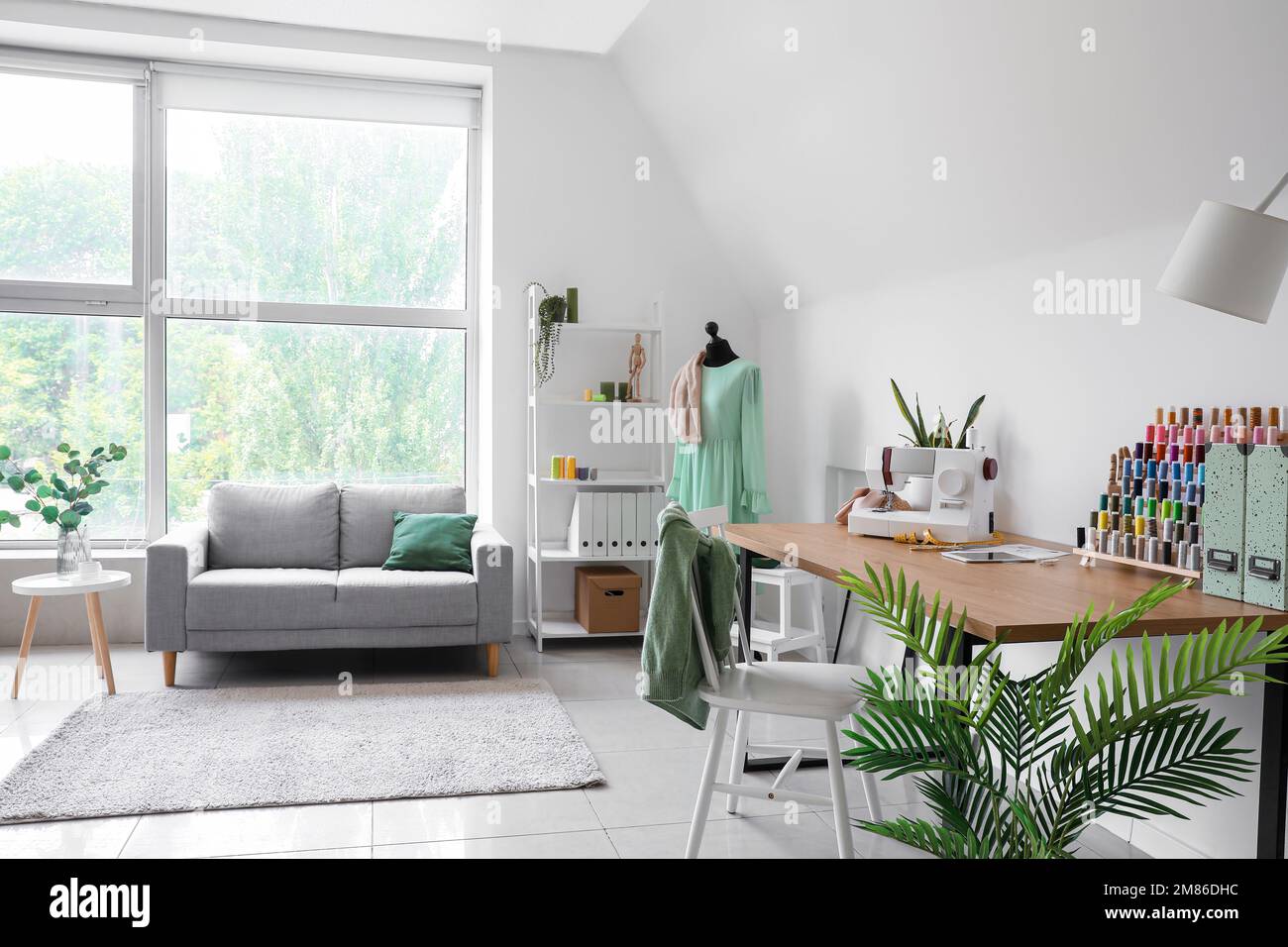 Interior of light atelier with tailor's workplace, mannequin and sofa ...