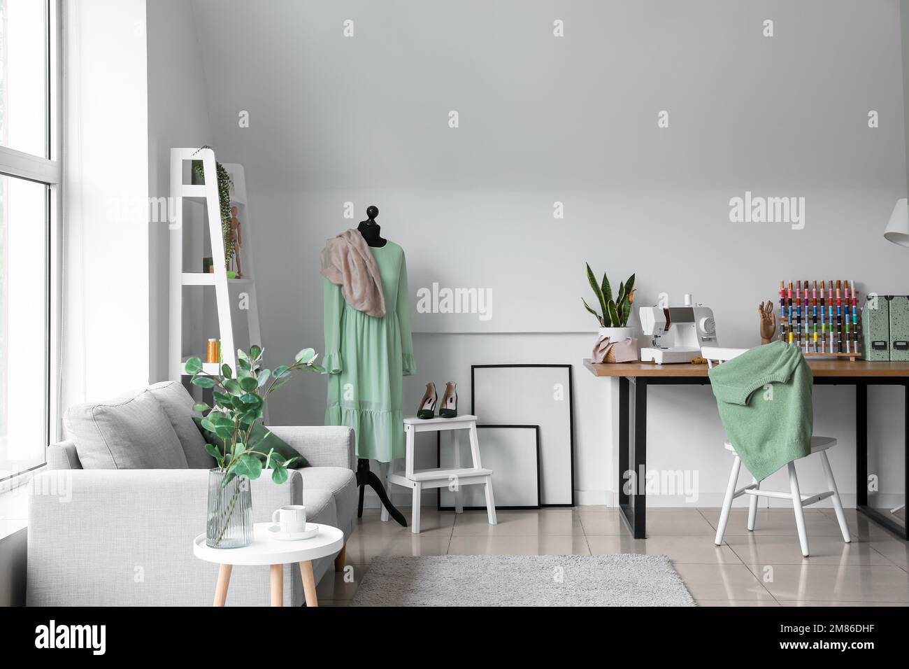 Interior of light atelier with tailor's workplace, mannequin and sofa ...