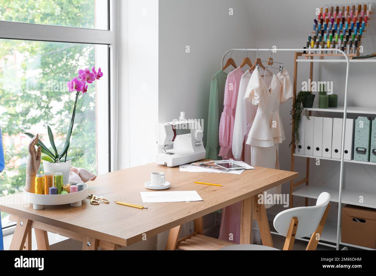 Tailor's workplace with sewing machine and supplies near window Stock ...