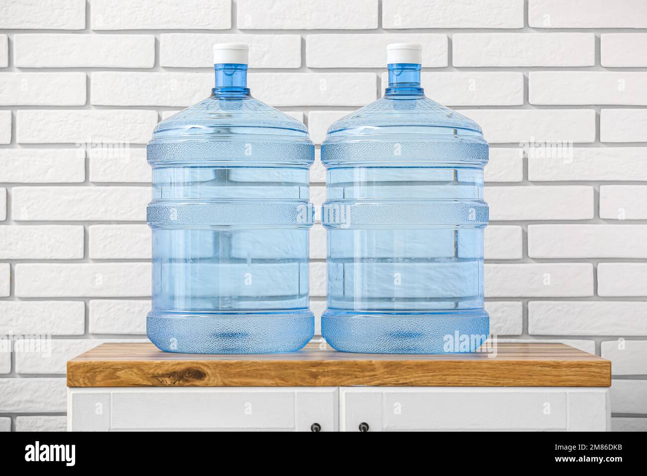 Bottles of clean water on counter near white brick wall Stock Photo - Alamy
