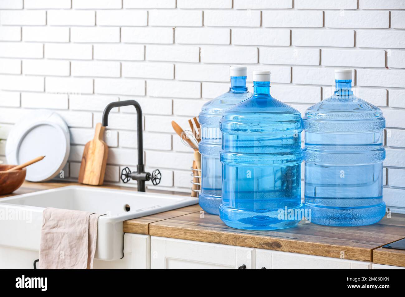 Bottles of clean water and sink on kitchen counter near white brick ...