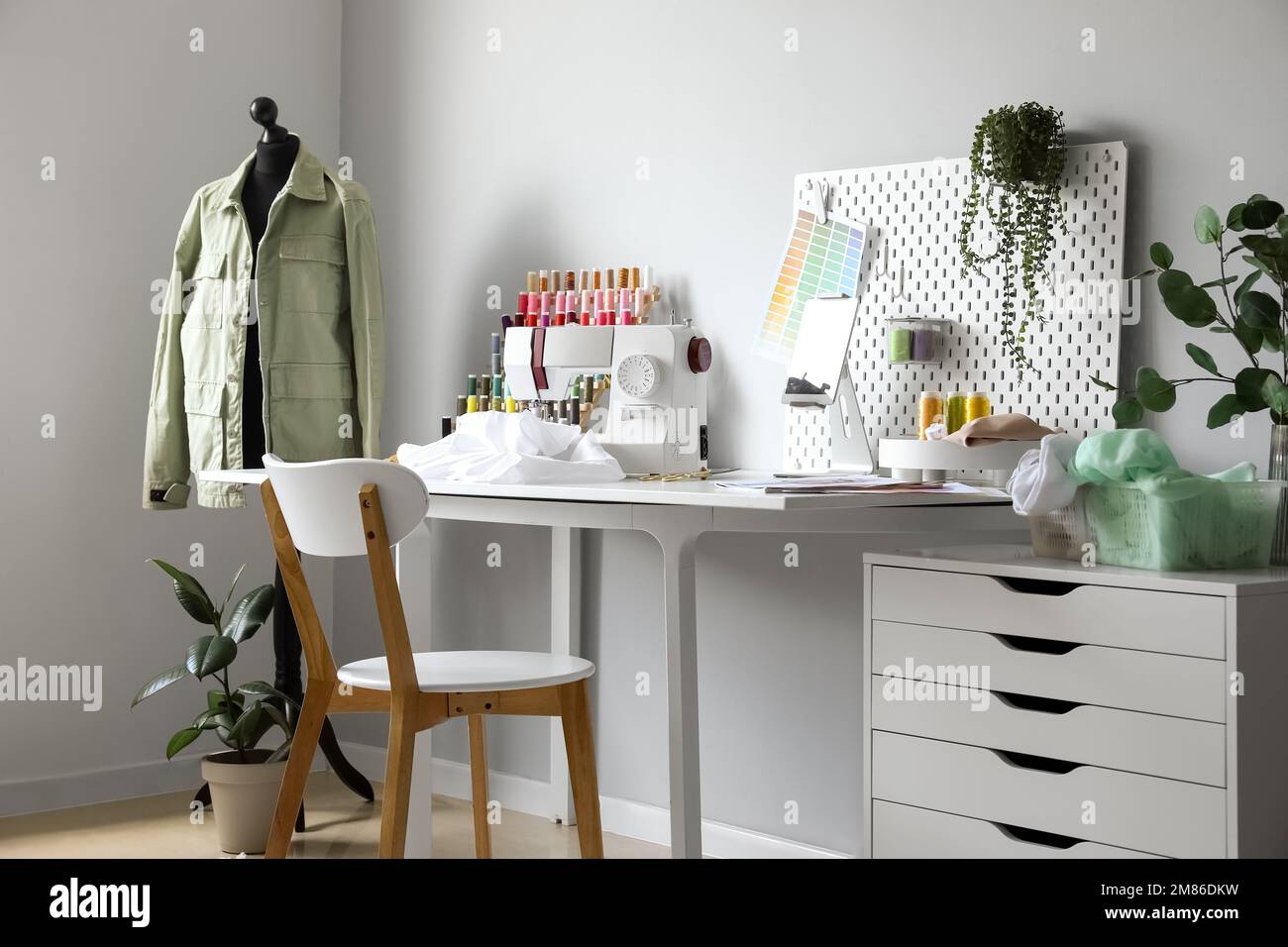 Tailor's workplace with sewing machine, pegboard and tablet computer in ...