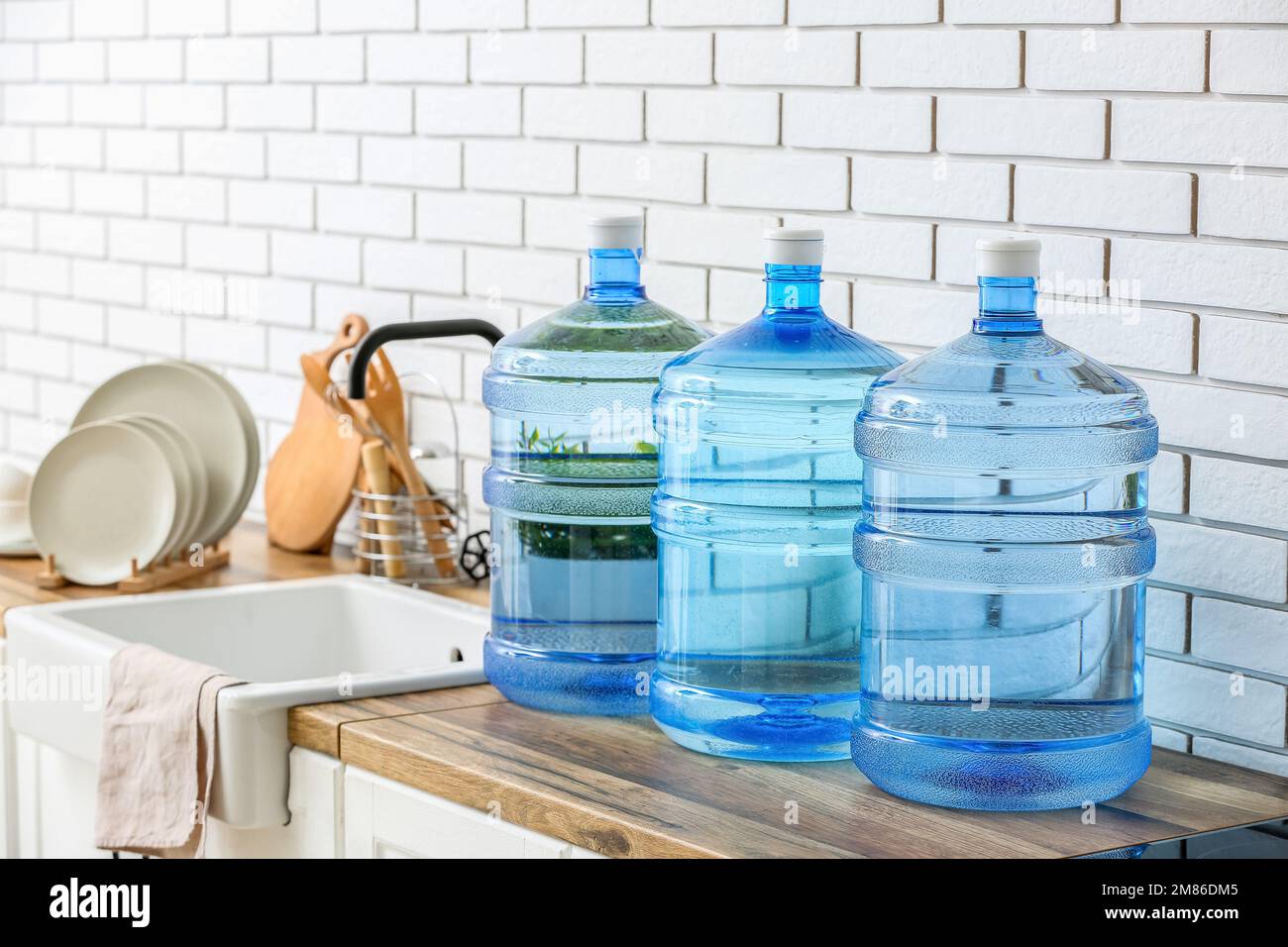 Bottles of clean water and sink on kitchen counter near white brick ...