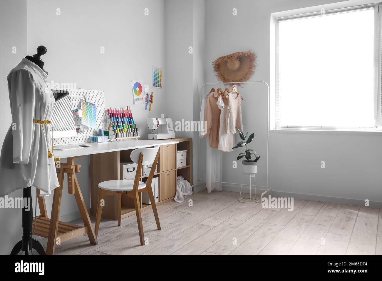 Interior of modern atelier with workplace, mannequin and clothes Stock ...