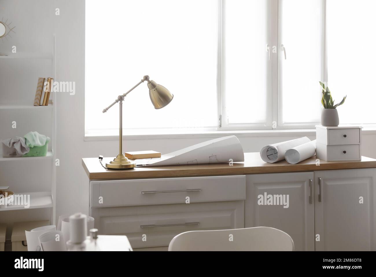 Tables with lamp and sewing patterns in modern atelier Stock Photo - Alamy