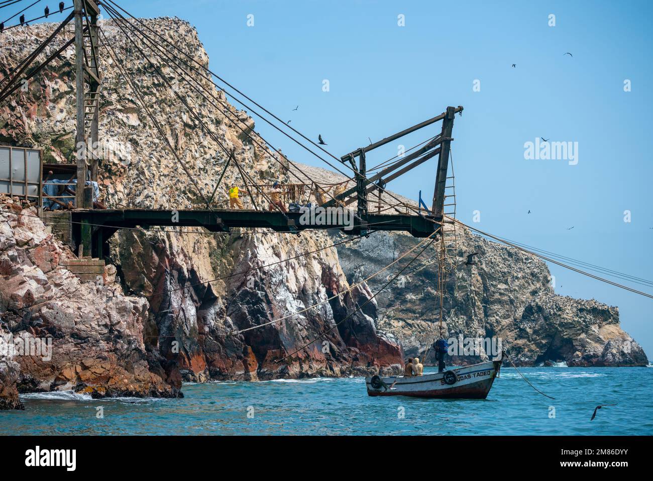 A boat on the sea surface under a wooden structure in the Ballestas ...