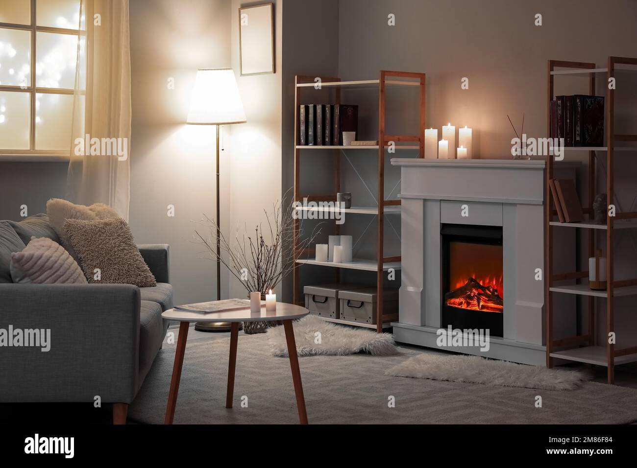 Interior of modern living room with fireplace, burning candles and ...