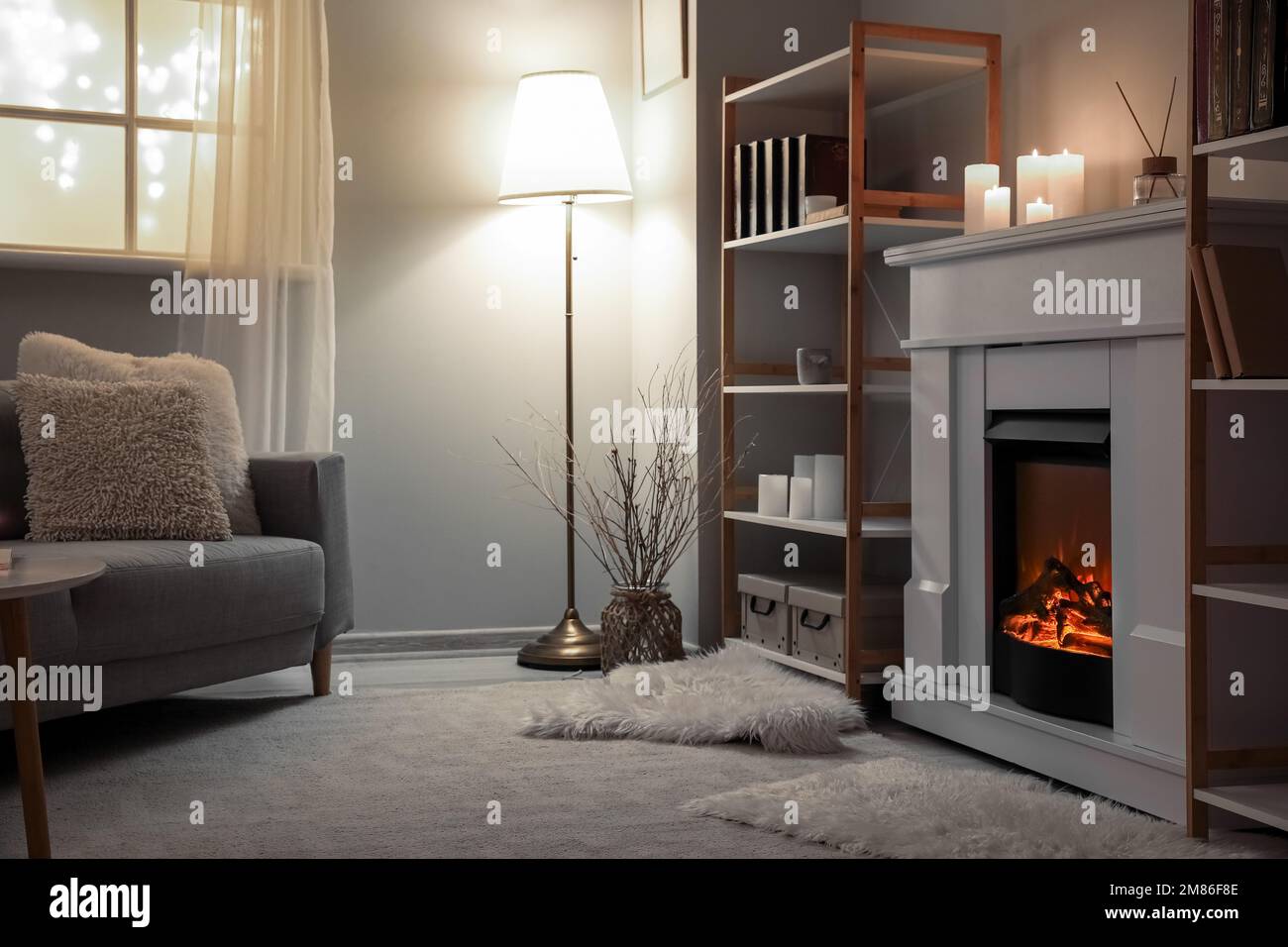 Interior of modern living room with fireplace, burning candles and ...