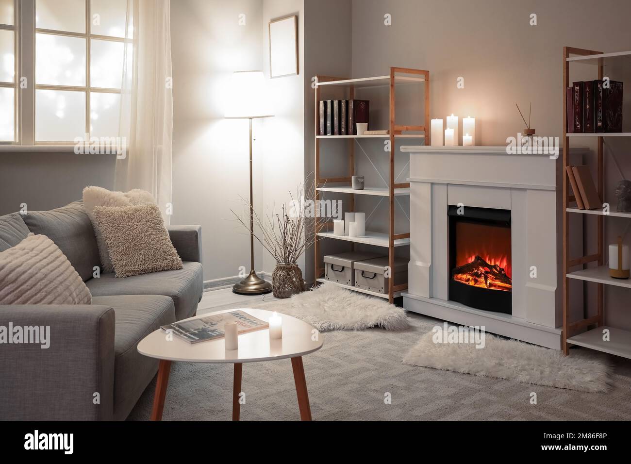 Interior of modern living room with fireplace, burning candles and ...