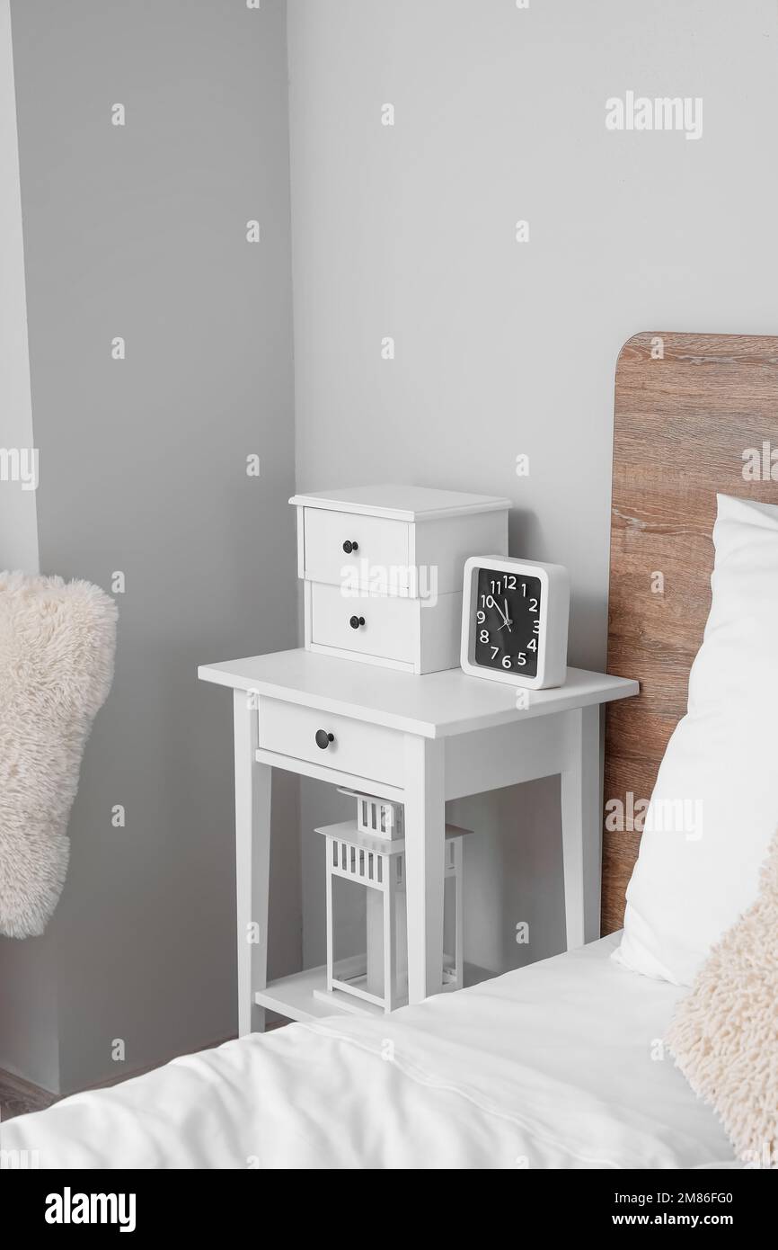 Bedside table with drawers and alarm clock in light bedroom Stock Photo ...