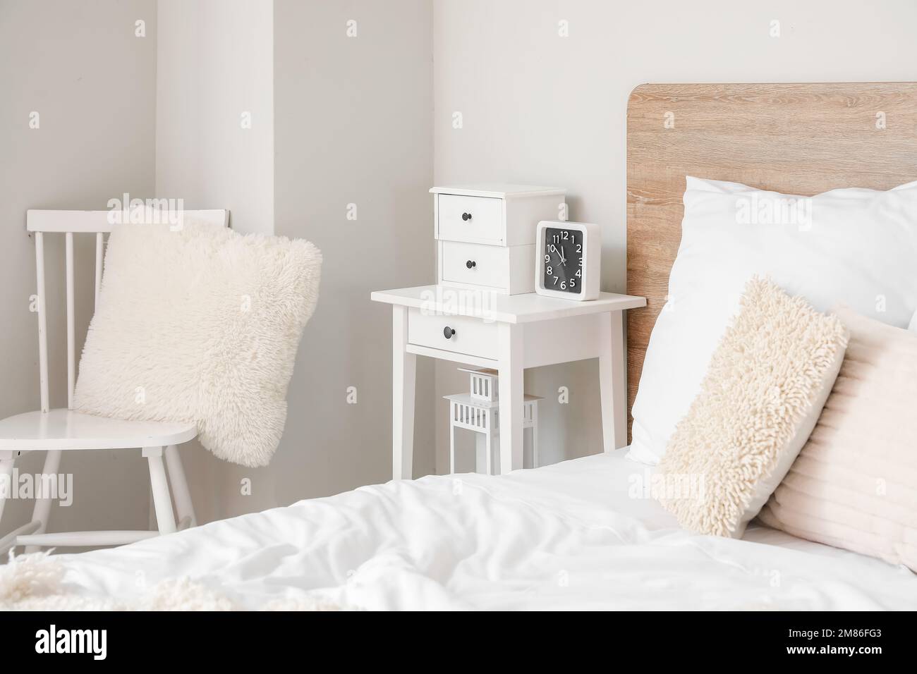 Bedside table with drawers and alarm clock in light bedroom Stock Photo ...