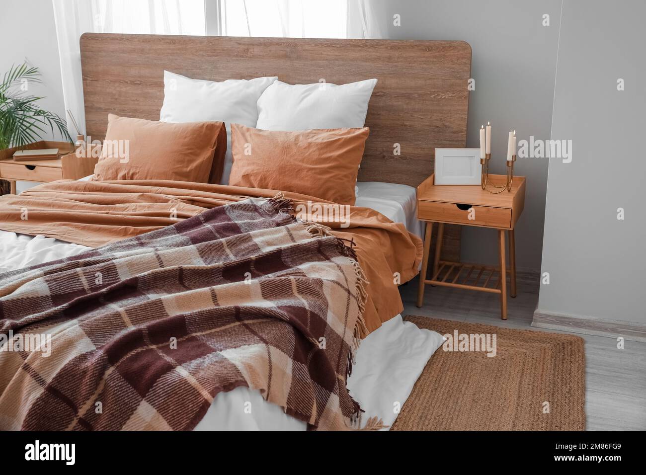 Big bed with wooden tables in interior of bedroom Stock Photo - Alamy
