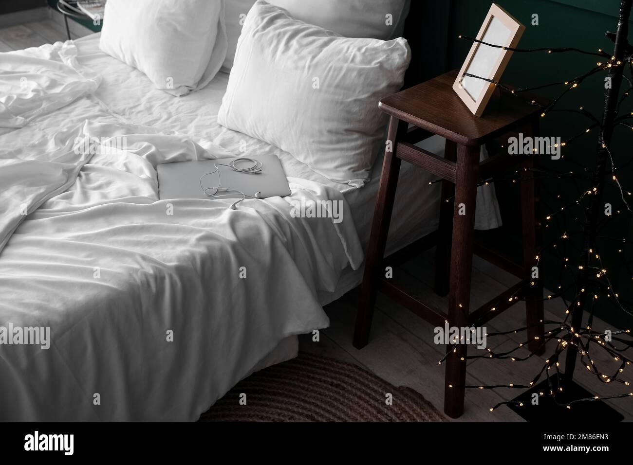 Bedside table with frame and glowing tree lamp in bedroom Stock Photo ...