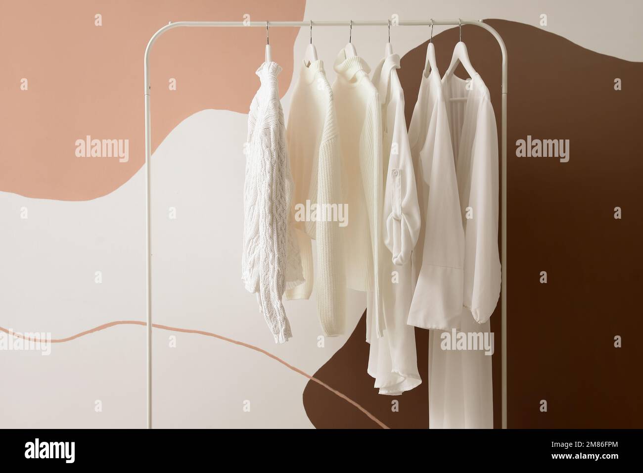 Rack with white female clothes near color wall Stock Photo - Alamy