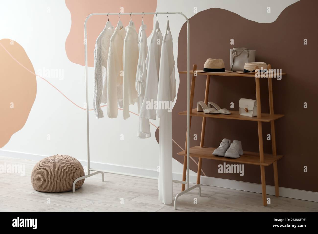Rack with white clothes, shelving unit and accessories near color wall ...