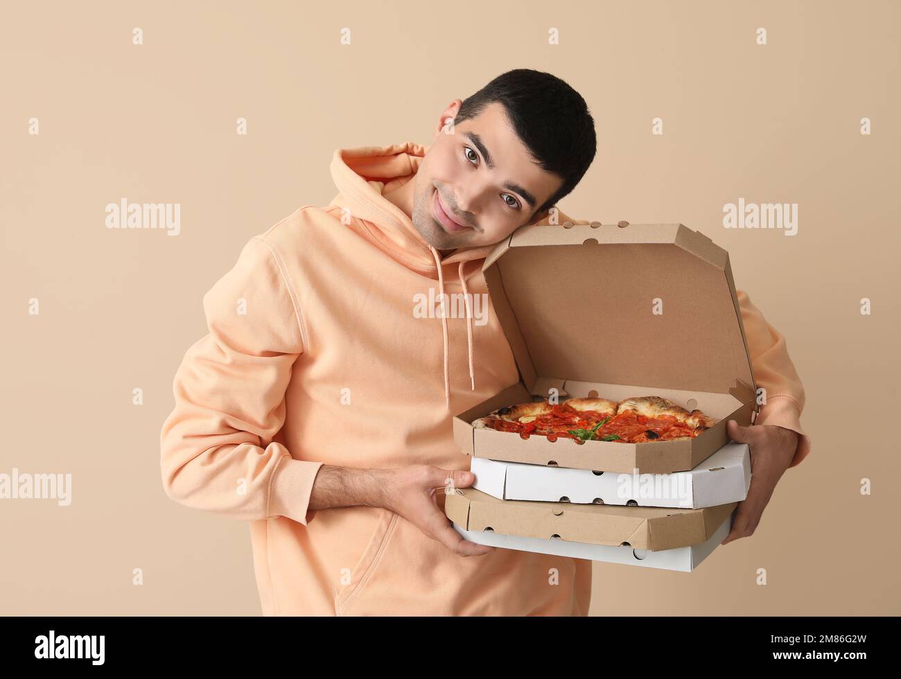 Young man with boxes of tasty pizza on beige background Stock Photo - Alamy