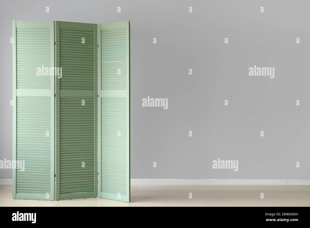 Green folding screen near grey wall Stock Photo - Alamy