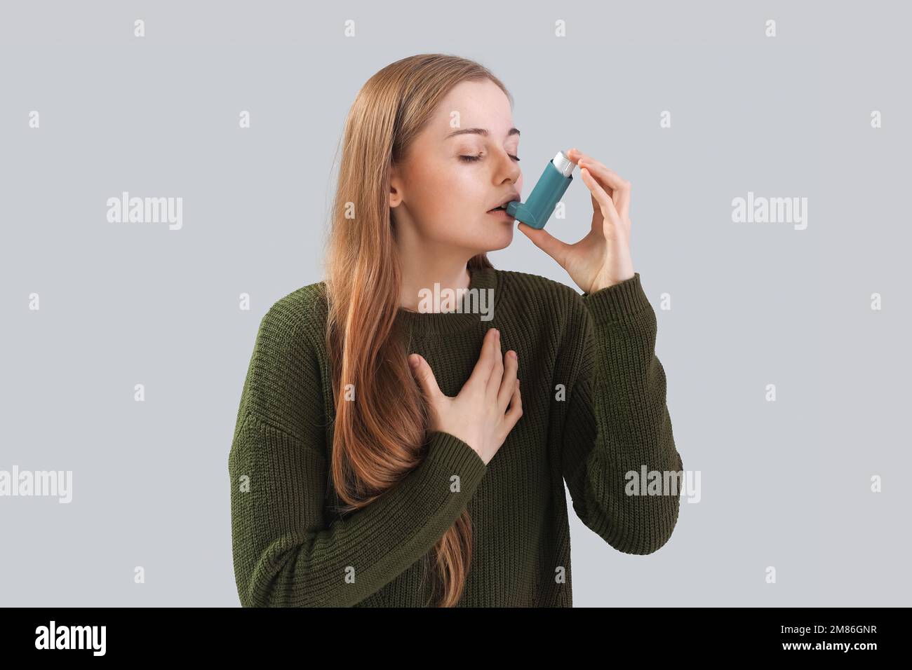 Young woman with inhaler on grey background Stock Photo - Alamy