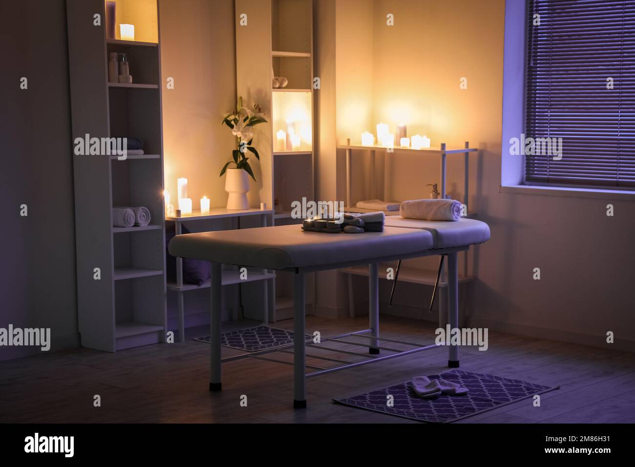 Interior of dark spa salon with couch, shelving units and burning ...