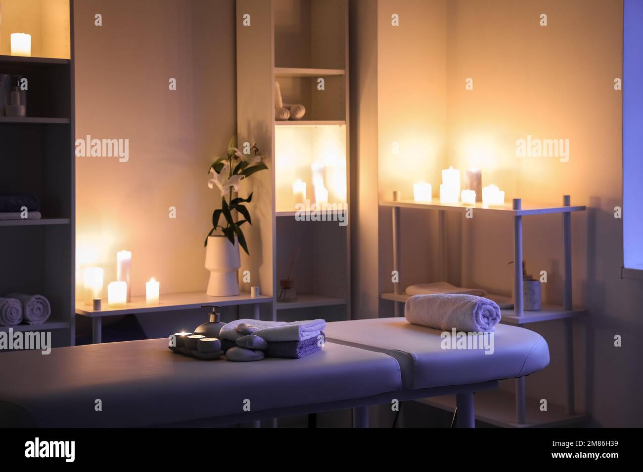 Interior of dark spa salon with couch, shelving units and burning ...