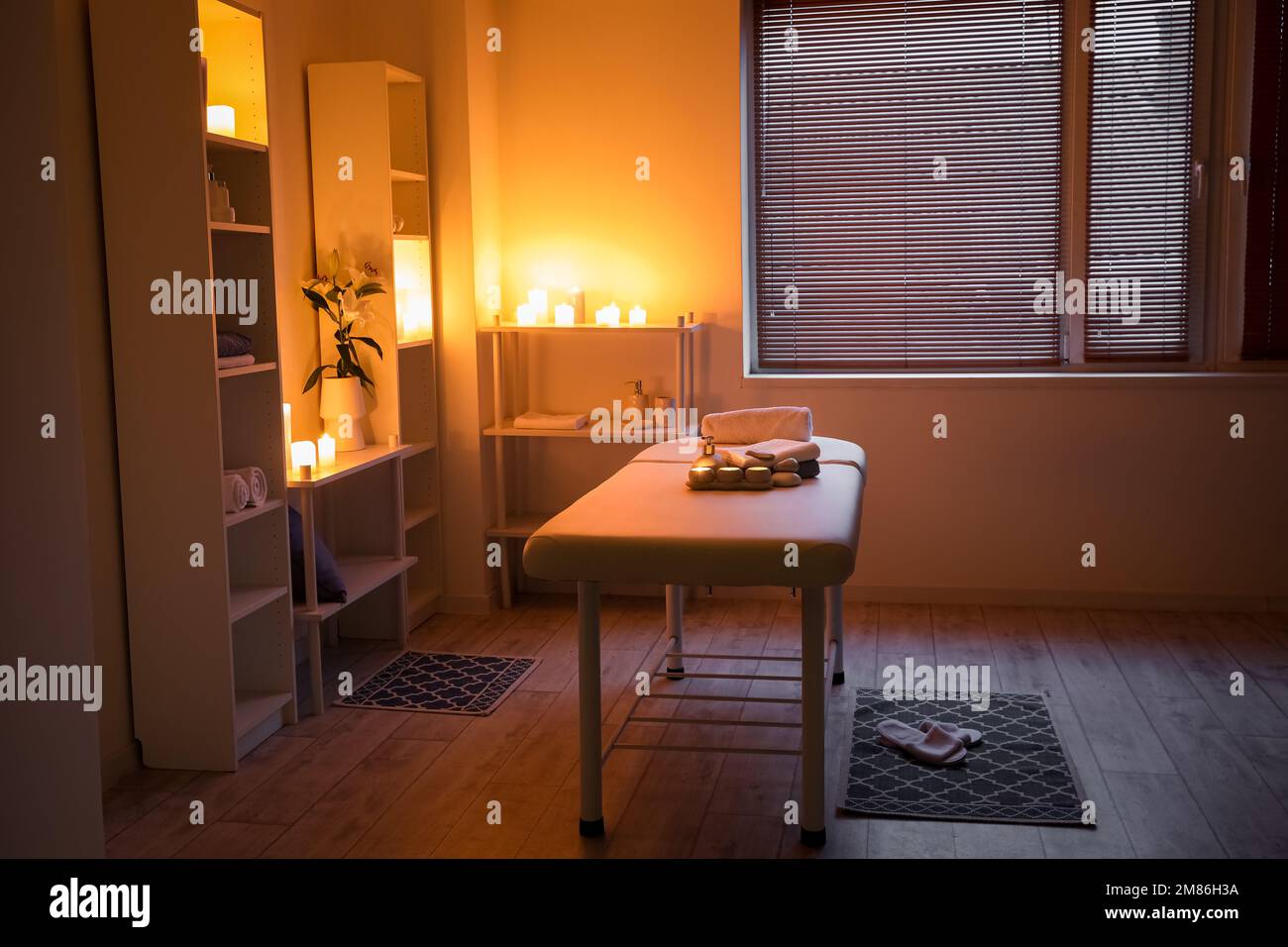 Interior of dark spa salon with couch, shelving units and burning ...