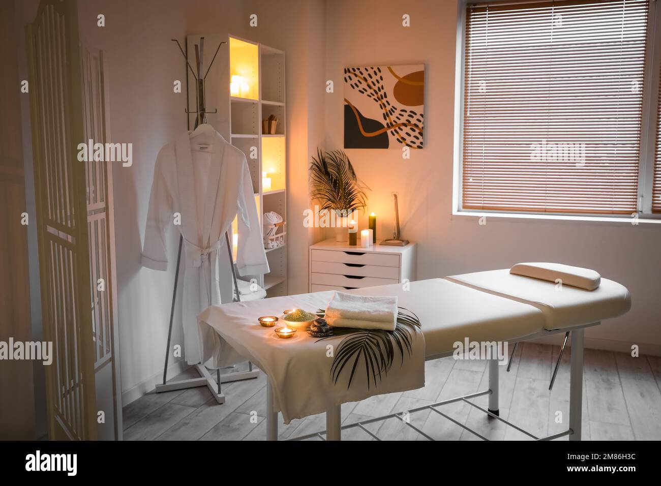 Interior of spa salon with couch, shelving unit and burning candles ...
